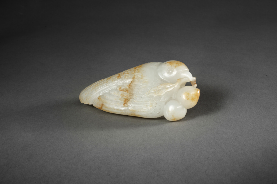 A RARE AND FINELY CARVED PALE GREENISH-WHITE AND RUSSET JADE `BIRD AND ...