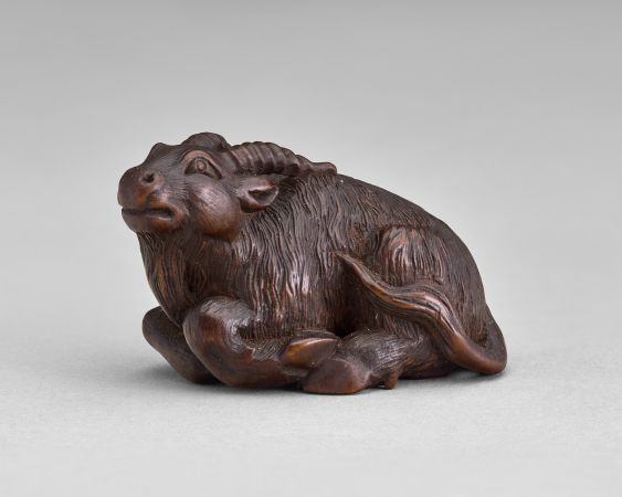 A CARVED WOOD NETSUKE OF A GOAT